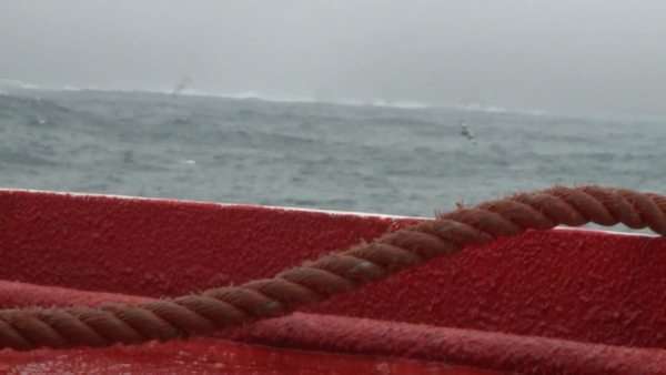 Close up of rope over edge of boat, rough, stormy Southern Ocean in ...