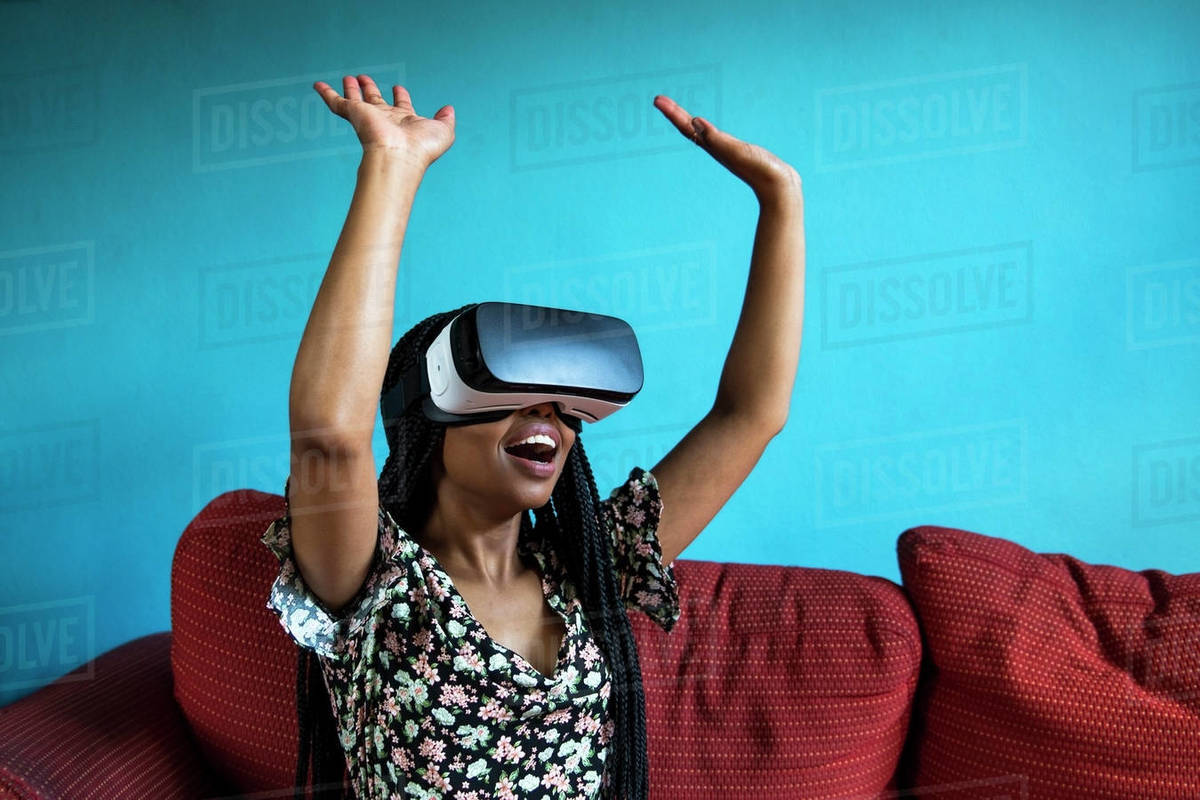 African woman looking through VR headset - Stock Photo - Dissolve