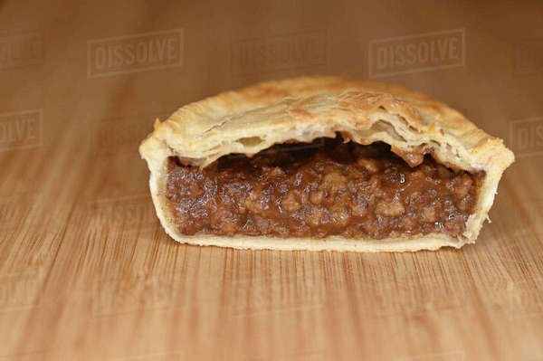Inside view of half of a hot meat pie on a wooden cutting board ...