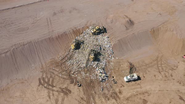 A landfill compactor, group of workers burying the garbage in the ...