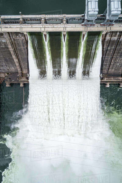 Aerial top down view of concrete dam releasing water into river on ...