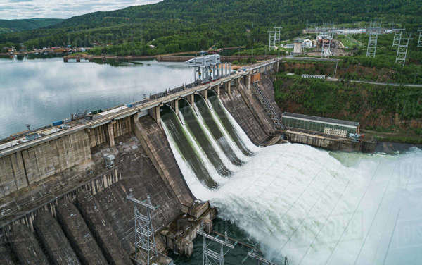 Aerial view of concrete dam releasing water into river on cloudy day ...