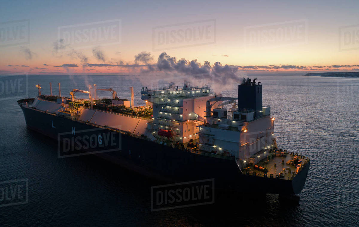 A large LNG tanker docks at an industrial port terminal for cargo ...