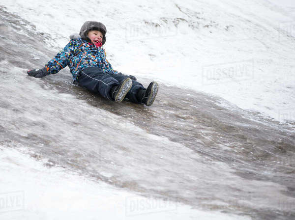 Child rides on an ice slide. Cheerful boy in the winter. - Royalty-free ...