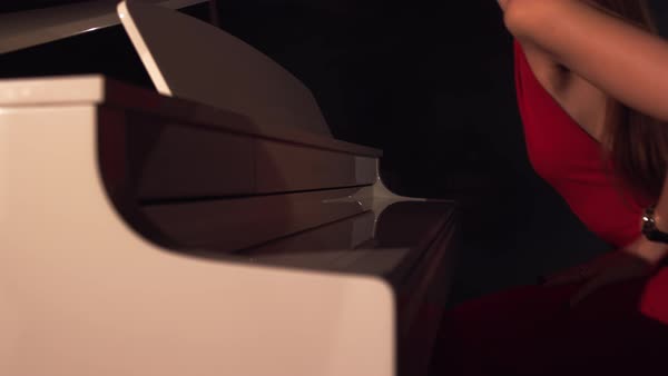 Woman pianists two hand opens the grand piano and starts playing ...