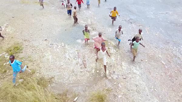 Aerial over African children running, playing and jumping up and down ...