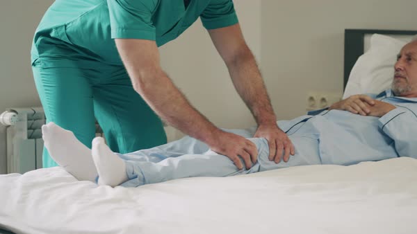 Trauma doctor examining upset senior patient lying on bed, injury ...
