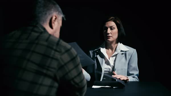 Female police detective showing photos of crime scene to suspect in ...