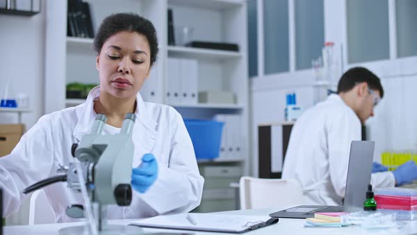 Busy microbiology lab scientist looking at sample substance through ...