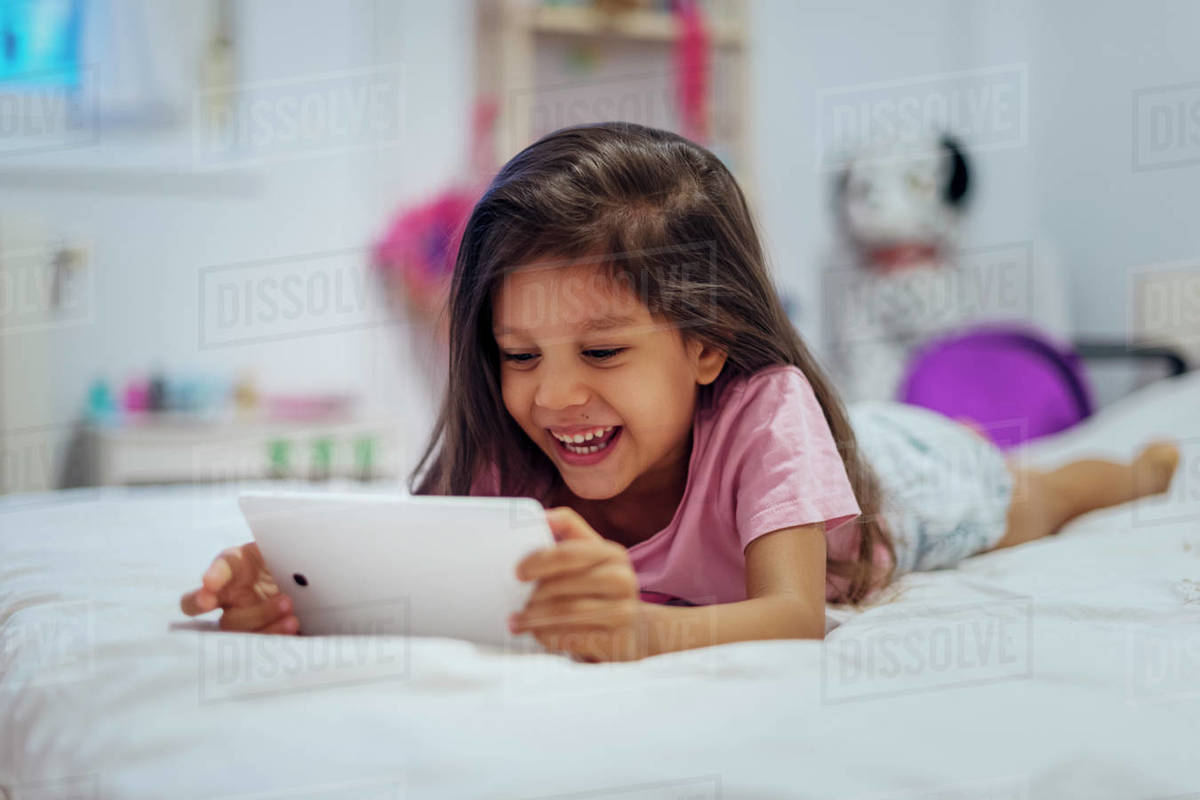 Hispanic kid having fun on tablet. - Stock Photo - Dissolve