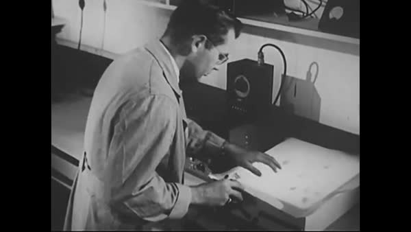 A scientist charts his findings while performing an experiment ...