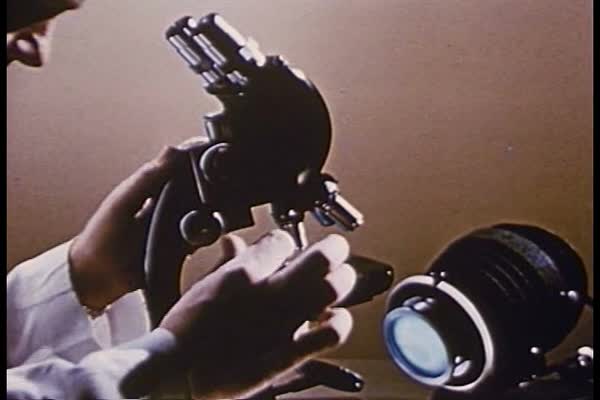 A scientist looks at cells under a microscope and an animation shows ...