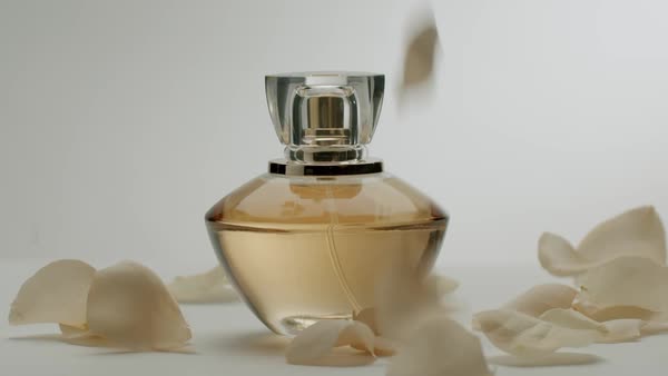 A glamorous perfume bottle surrounded by delicate rose petals falling ...