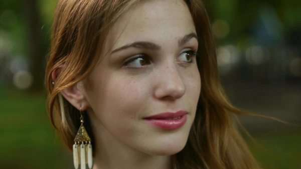 Beautiful young woman looks off into distance, then smiles at camera ...