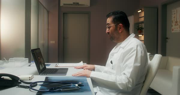 A doctor records himself on video on a laptop, recording a video course ...