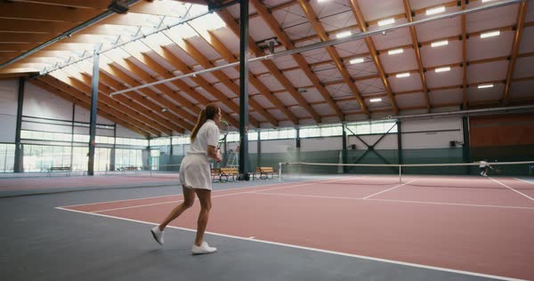 Tennis practice in an empty indoor tennis court. Young athletes throw ...