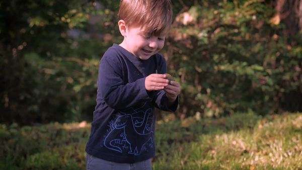 A beautiful young blond boy bending over and picking something up from ...