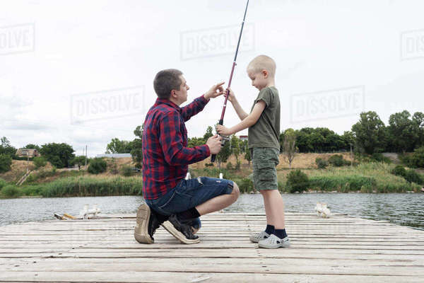 Father and son fishing. Dad shows his son how to hold the spinning and ...