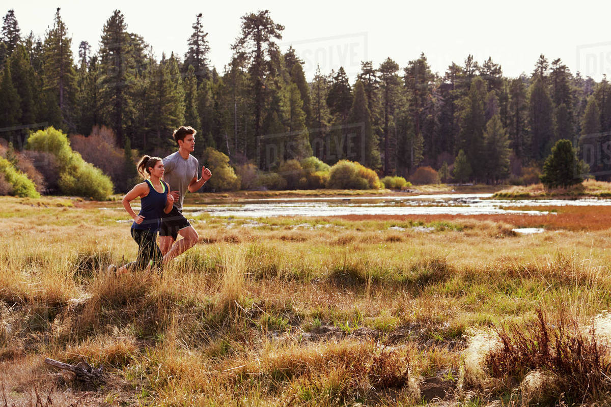 Man and woman running in nature near a lake, side view - Stock Photo ...
