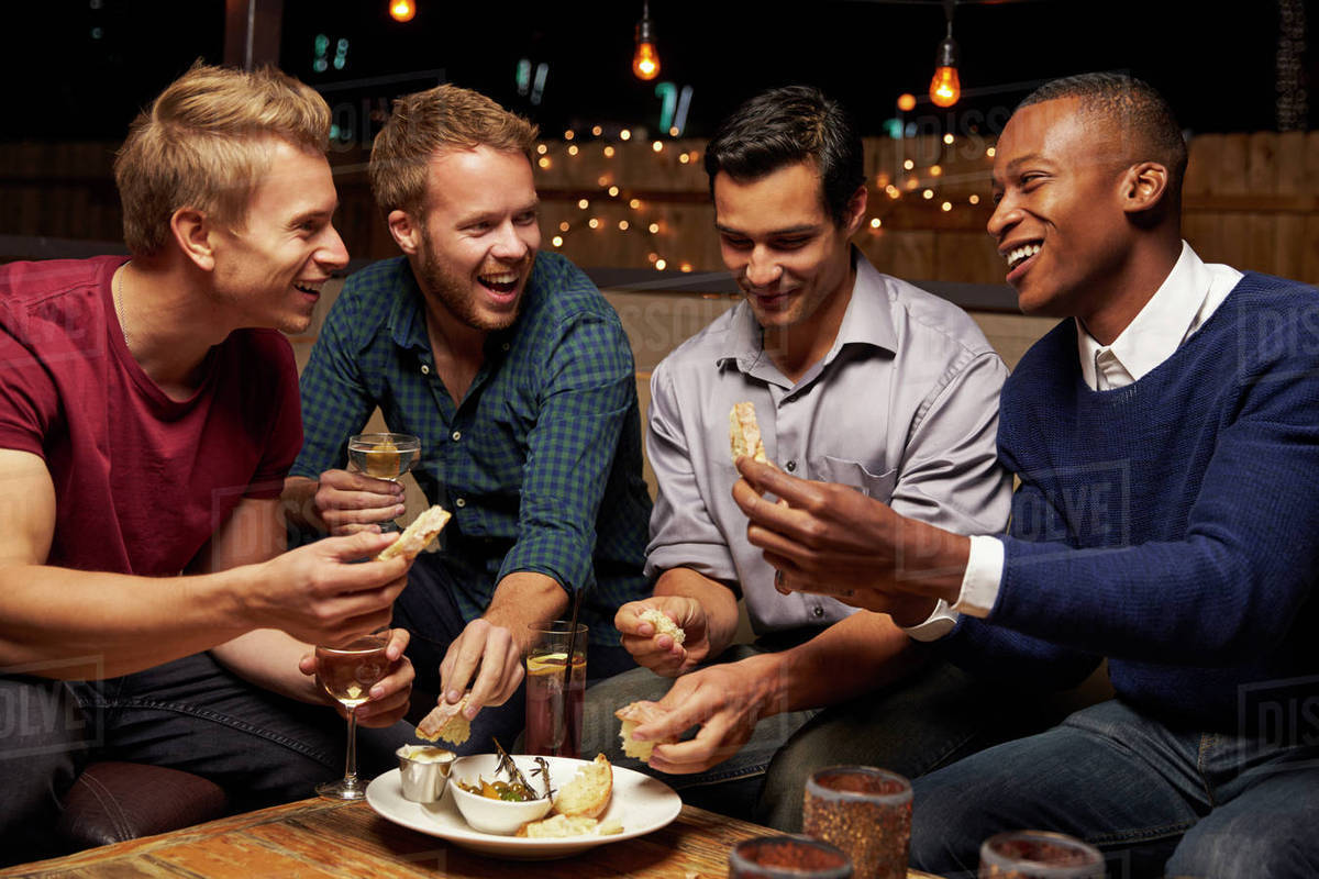 Group of male friends enjoying night out at rooftop bar - Stock Photo ...
