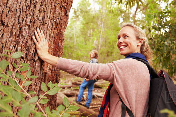 Woman touching a tree in a forest, her son in the background - Stock ...