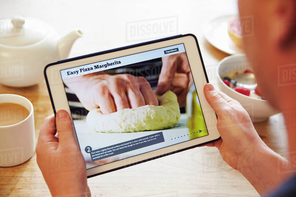 Person at breakfast looking at recipe app on digital tablet - Stock ...