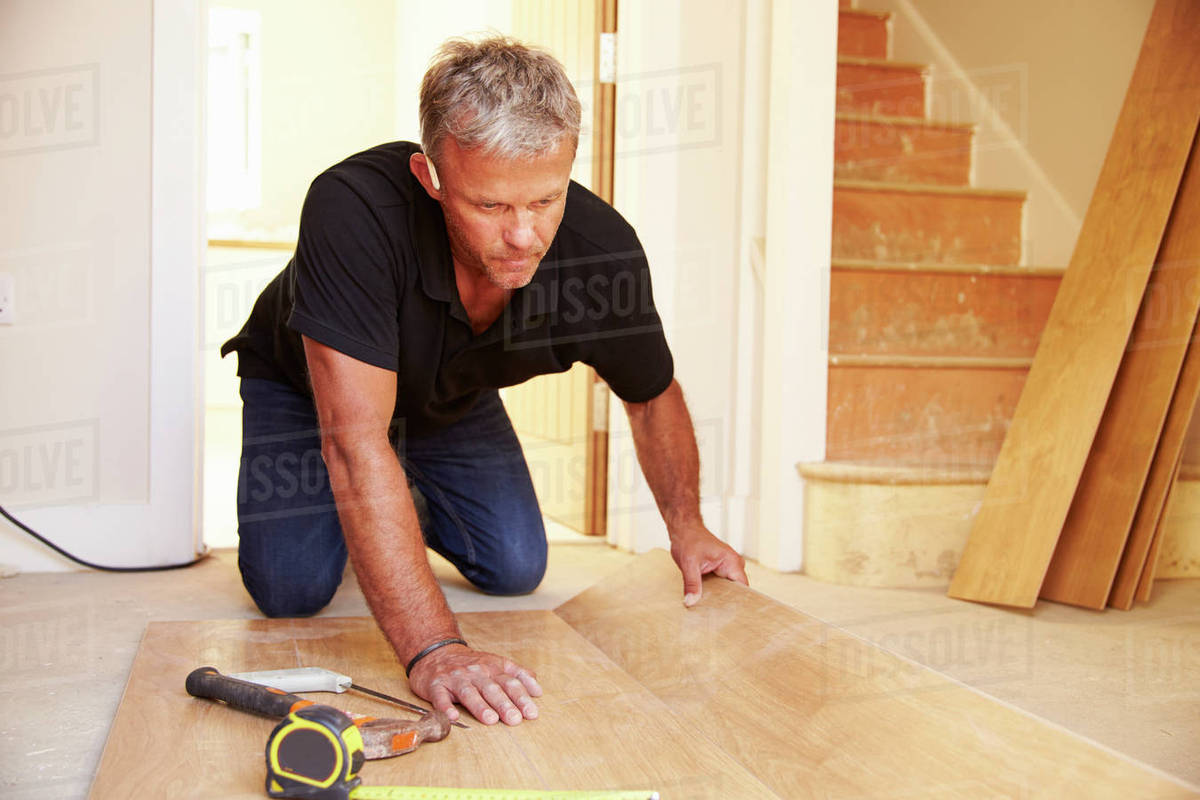 Man laying wood panel flooring during a house refurbishment - Royalty ...