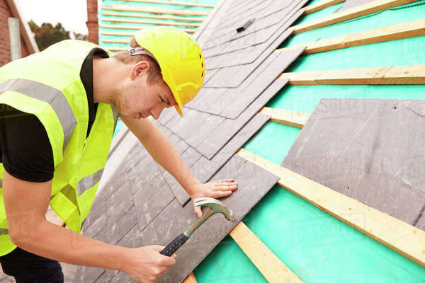Construction worker on building site laying slate tiles - Royalty-free ...