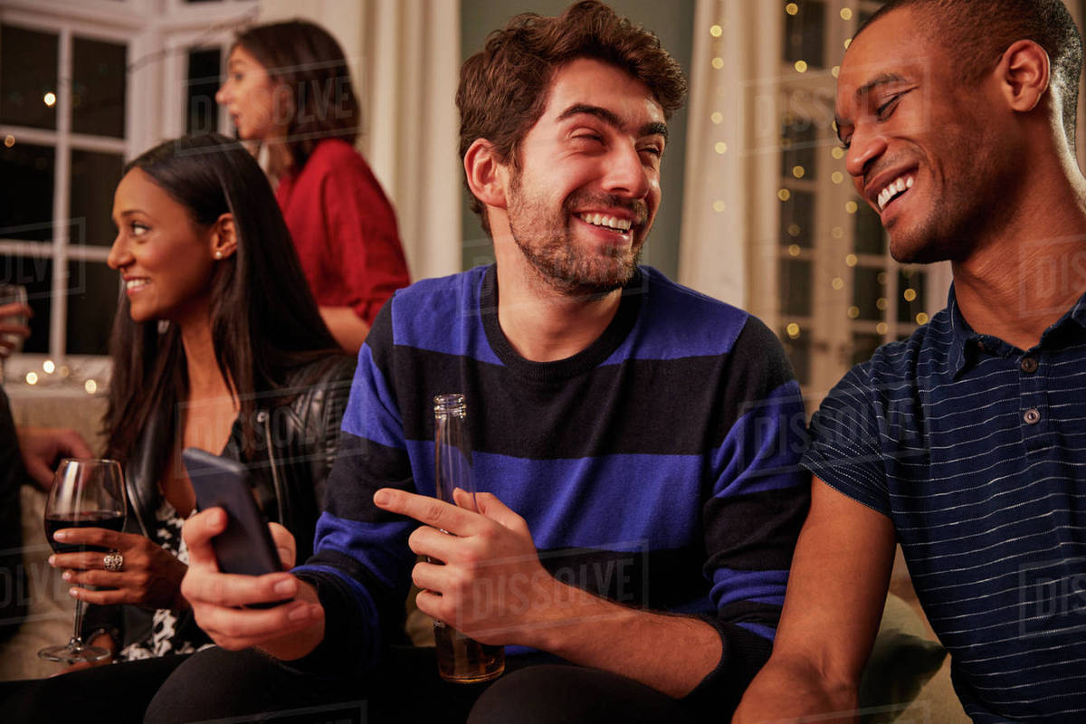 Man looking at message on mobile phone at party - Royalty-free Stock ...