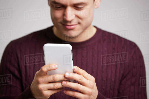 Close up of smiling young white man using a smartphone - Royalty-free ...
