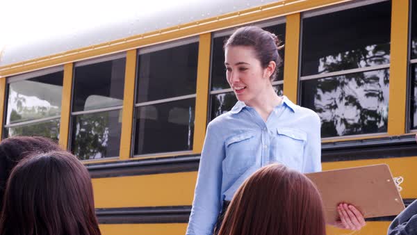 Elementary school teacher and kids talking by school bus - Stock Video ...
