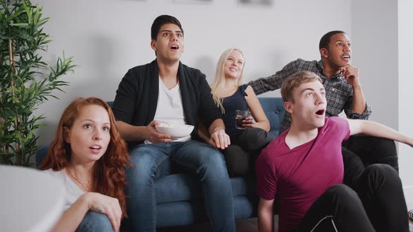 Group of college student friends celebrating whilst watching sports ...