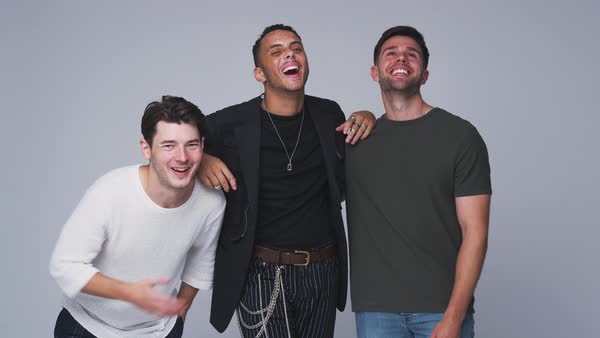 Group of male friends in studio laughing and smiling into camera in ...