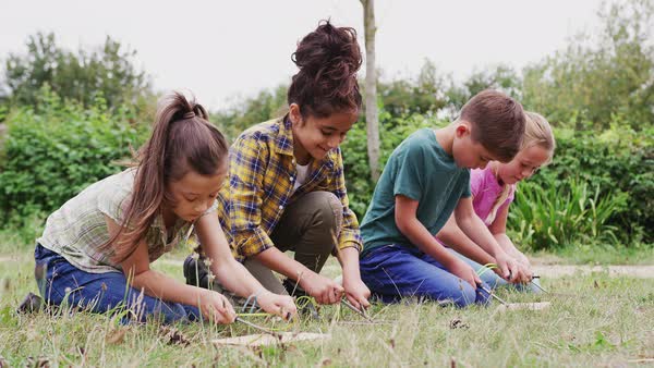 Group Of Children On Outdoor Camping Trip Learning How To Make Fire ...