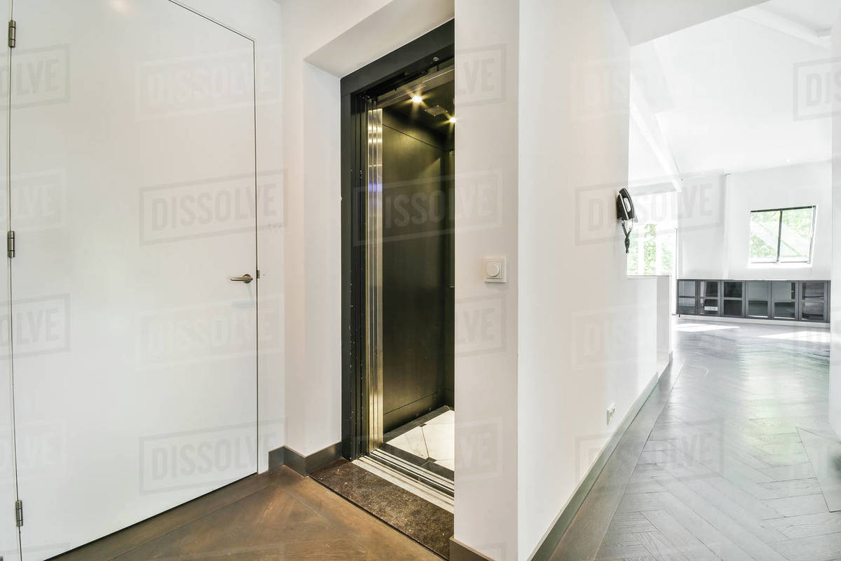 Interior of spacious hallway with metal elevator and tiled floor in ...