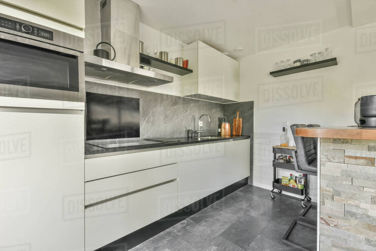 Luxury kitchen in shades of gray with a worktop and high-legged chairs ...