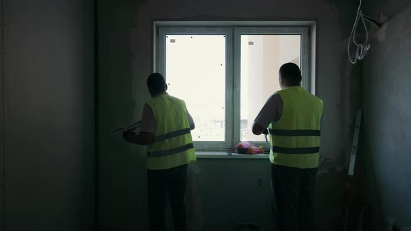 Internal construction works. Silhouette of two craftsmen plastering the ...