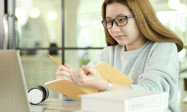 A teenage student eagerly taking notes from her laptop, wearing a gray ...