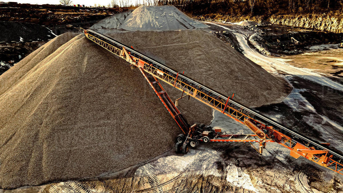 Open-pit rock quarry with conveyor system carrying freshly cut stone ...