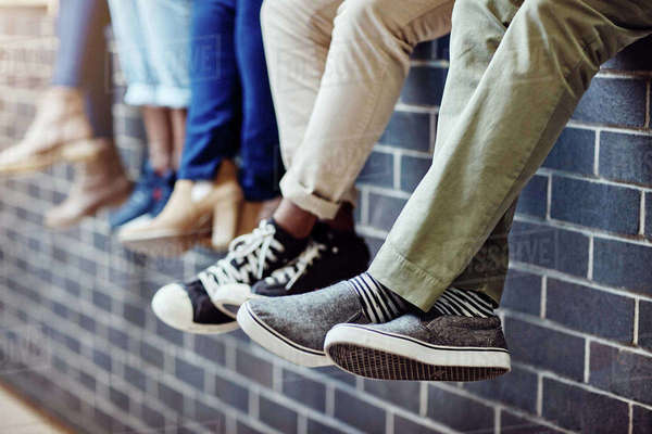 Brick wall, student feet and friends outdoor on university campus ...