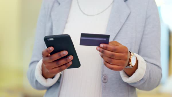 Woman making an online payment on her phone with a credit. Closeup of a ...