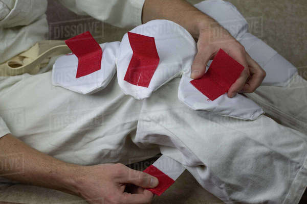 Karate athlete puts on training protection on his legs, knee protection ...