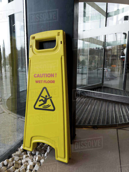 Vertical photograph of wet floor warning sign. Yellow fold out sign to ...
