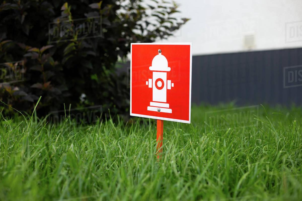 Red square plate with a white sign of a hydrant on a lawn in the grass ...