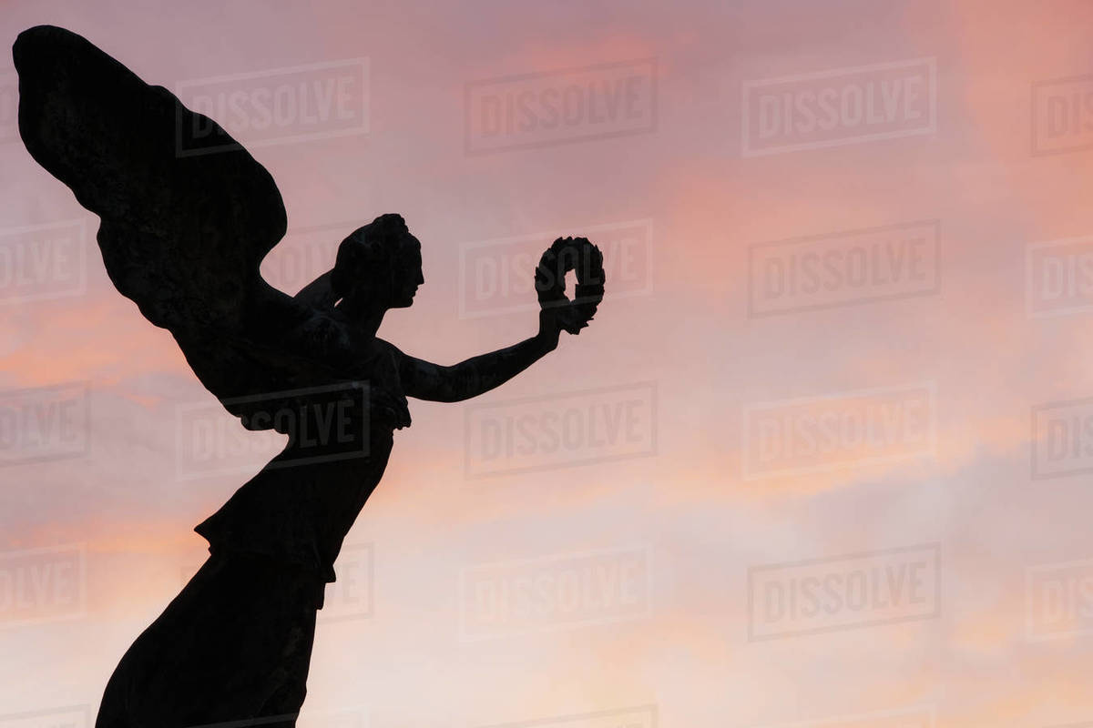 Winged victory statue silhouette against pink clouds at Altare della ...