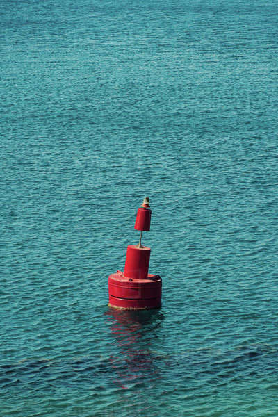 Big red iron navigational buoy with signaling light floating on a blue ...