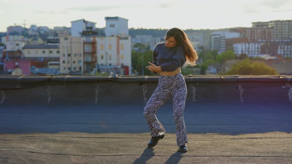 Attractive caucasian hip-hop woman dancing on the roof floor staring at ...