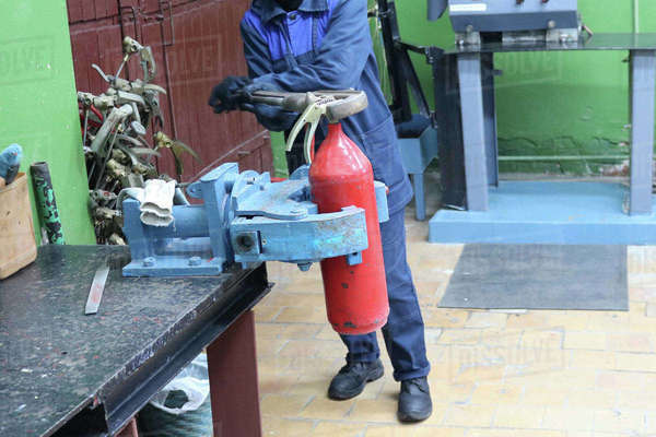 A man working on a large metal industrial vice with a huge gas wrench ...