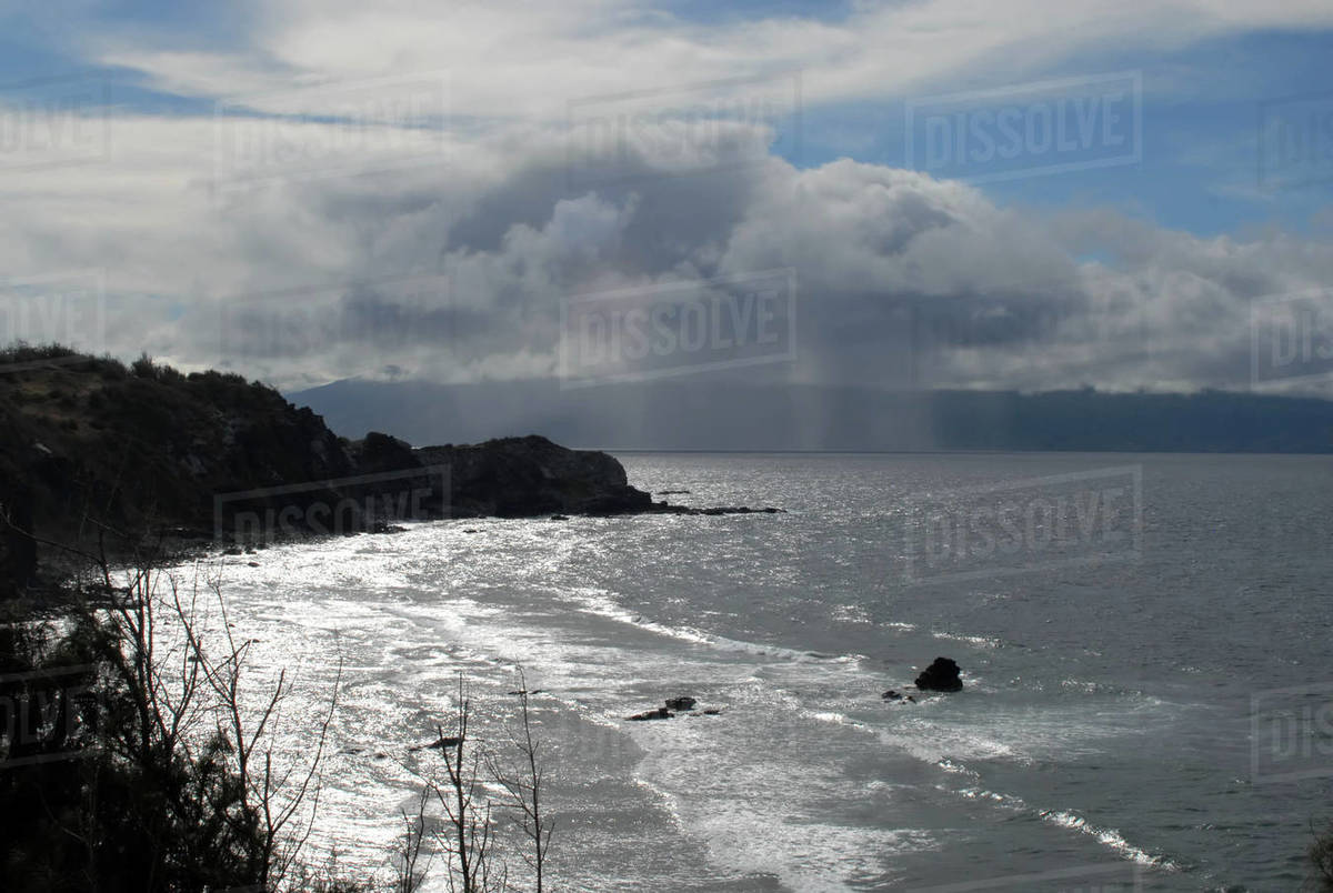 Low rain cloud and reflected sunlight on ocean at seaside between ...