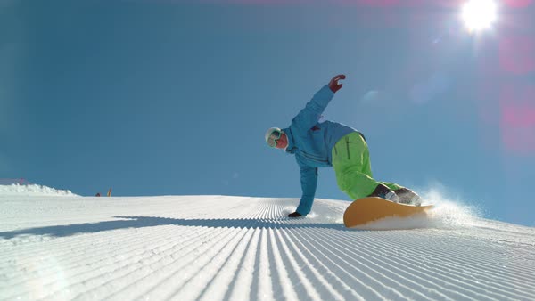 SLOW MOTION, LOW ANGLE, LENS FLARE: Cheerful young male snowboarder ...